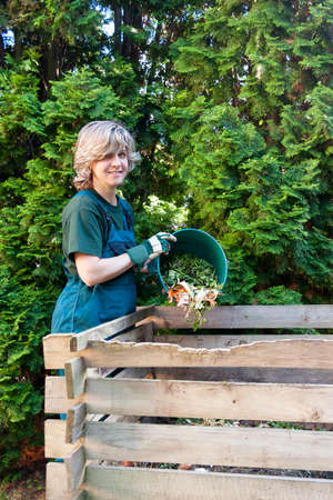 Young, smiling caucasian female emptying a bucketful of compost to the ...