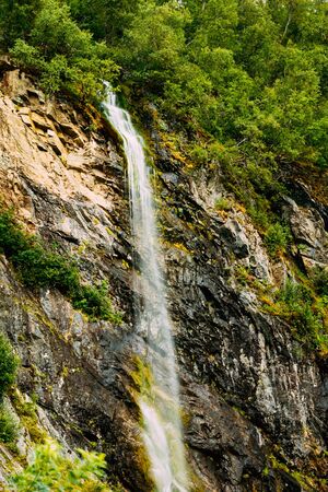Thin water stream flowing from rocky slope of Norwegian mountains ...