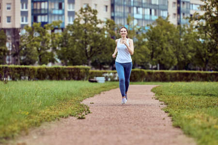 Young woman is jogging in morning in park area of residential area of ...