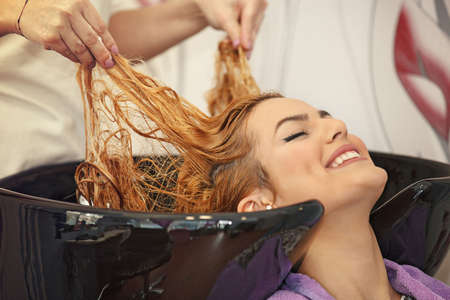 Young beautiful blonde woman enjoying hair treatment. - Stock Image ...