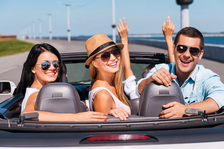 Friends in convertible. Group of young happy people enjoying road trip ...