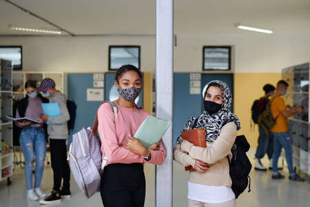 Young students friends with face masks back at college or university ...