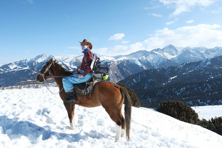 Freeride on horseback. A man in a cowboy hat riding a horse in the snow ...