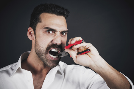 Young handsome man with beard and mustache pulling out his tooth with ...