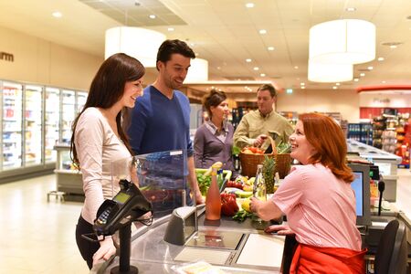 people shopping at the supermarket - paying at the checkout with a ...