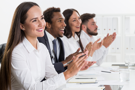 Group of colleagues applauding to some person off camera while sitting ...