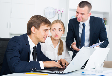 Three concerned coworkers different sexes working on computers together ...