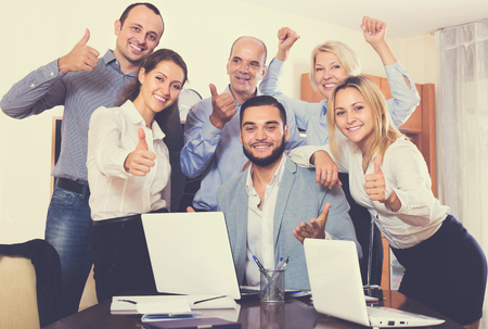 Portrait of friendly relaxed employees sitting at desk - Stock Image ...