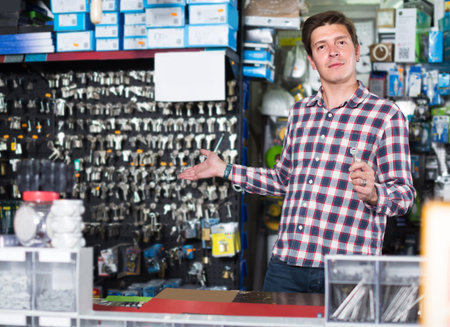 Cheerful american worker in hardware store trading goods and keys in ...