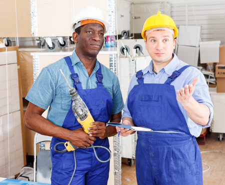 Focused construction workers discussing while inspecting room and ...