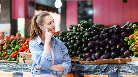 Sad unhappy female is standing dissatisfied near shelves with ...