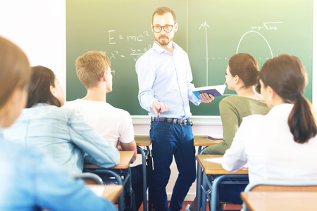 Positive man teacher is giving interesting lecture for students during ...