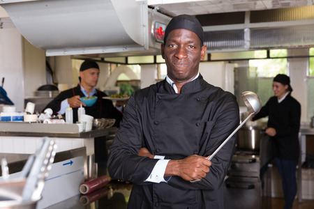 Portrait of confident African American chef in restaurant kitchen with ...
