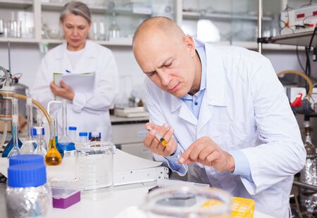 Professional biochemist performing experiments in lab room, mixing and ...