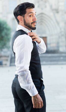Handsome smartly dressed man standing outdoors shaking dust off ...