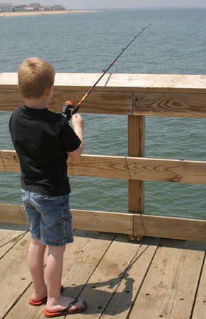 A little boy reeling in his fishing line.の写真素材 [40000417595] - イメージマート