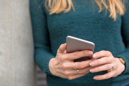 Woman browsing on her mobile phone in a close up view of her hands in ...