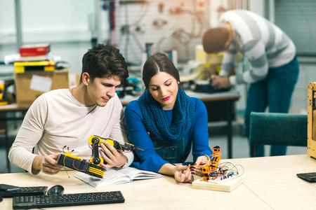 Young students of robotics preparing robot for testing in workshop ...