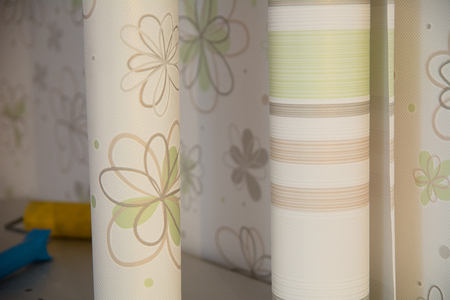 Two rolls of wallpaper stand against the wall with floral wallpaper ...