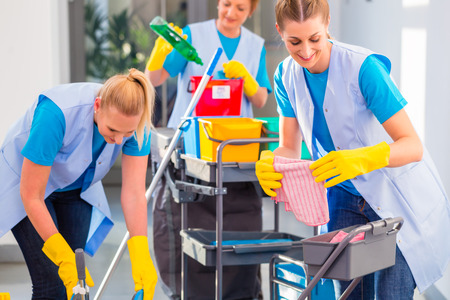 Commercial cleaners doing the job together, three women with trolley ...
