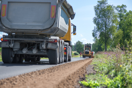 Road construction workers repairing highway road on sunny summer day ...
