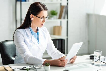 interested doctor in earphones having online consultation on digital ...