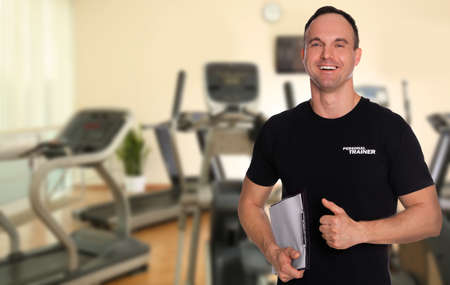 Portrait of professional personal trainer with clipboard in gym. Space ...
