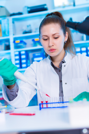 A young chemist holding test tube with liquid during chemical ...