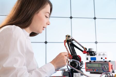 A young woman writes an algorithm for the robot arm. Science Research ...