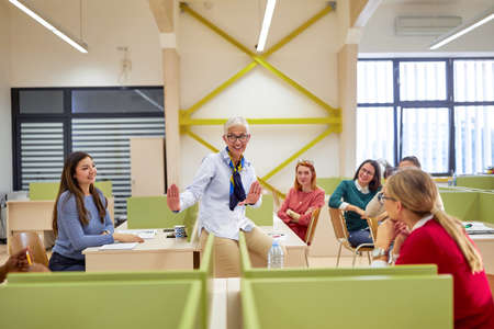 A female professor in a good mood explaining the lesson to students in ...