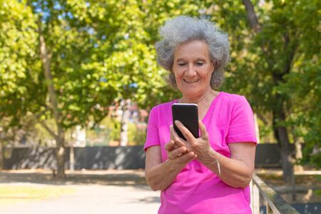 Joyful happy old lady using cellphone for video call in park. Senior ...