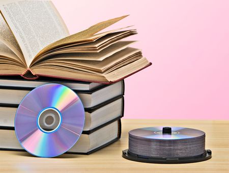 Pile of books and DVD disk as symbols of old and new methods of ...