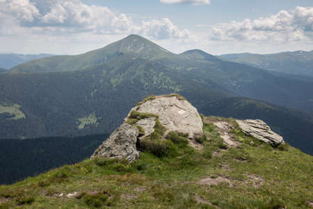 The top of Mount Hoverla is covered with green grass and stones on a ...