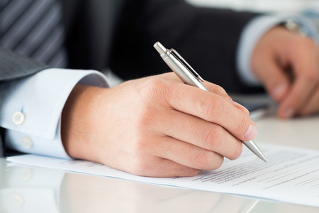 Close-up of businessman hands signing documents. Man writing something ...
