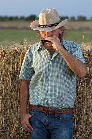 Cowboy with Hay Bale Playing Harmonicaの写真素材 [40010429875] - イメージマート