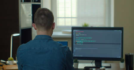 Young man freelancer coding html and programming on two screen Monitors ...