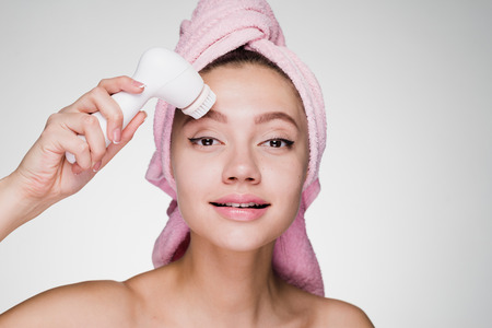 woman with a towel on her head cleans the face with a brush for deep ...