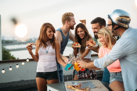 Friends having fun and drinking outdoor on a rooftop get together ...
