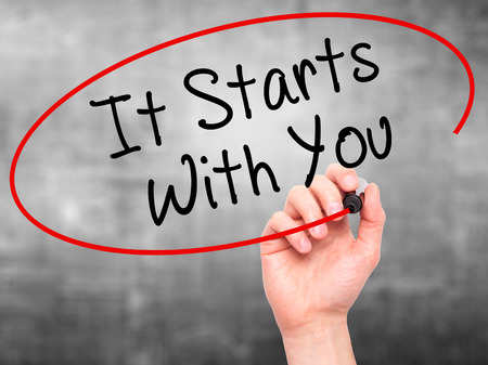 Man Hand writing It Starts With You with black marker on visual screen ...