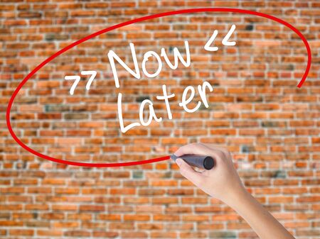 Woman Hand Writing Now/Later with black marker on visual screen ...