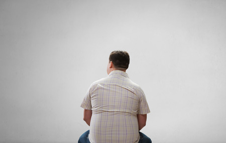 Fat man sitting on bench with his back and looking away - Stock Image ...