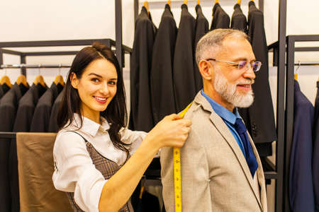 a professional tailor woman trying on a tailor-made suit for an elderly ...