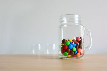 colorful button-shaped candies coated chocolate sweets in glass bottle ...