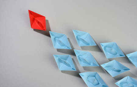 group of paper boats on a gray background. concept of a strong leader ...