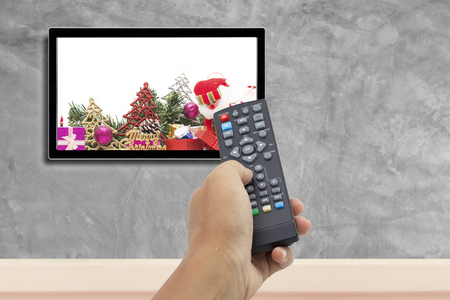 Christmas decoration with hand holding remote control at the television ...
