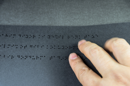 Top view of hand of a blind person reading a book written in braille ...