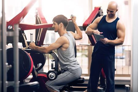 The trainer controls the physical exercise of the man on the training ...