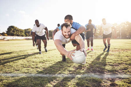 Caucasian rugby player diving to score a try during a rugby match ...