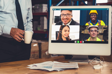 Warehouse staff talking on video call at computer screen in storage ...