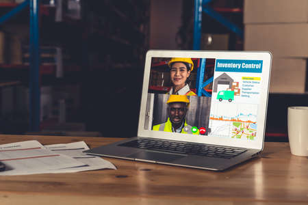 Warehouse staff talking on video call at computer screen in storage ...